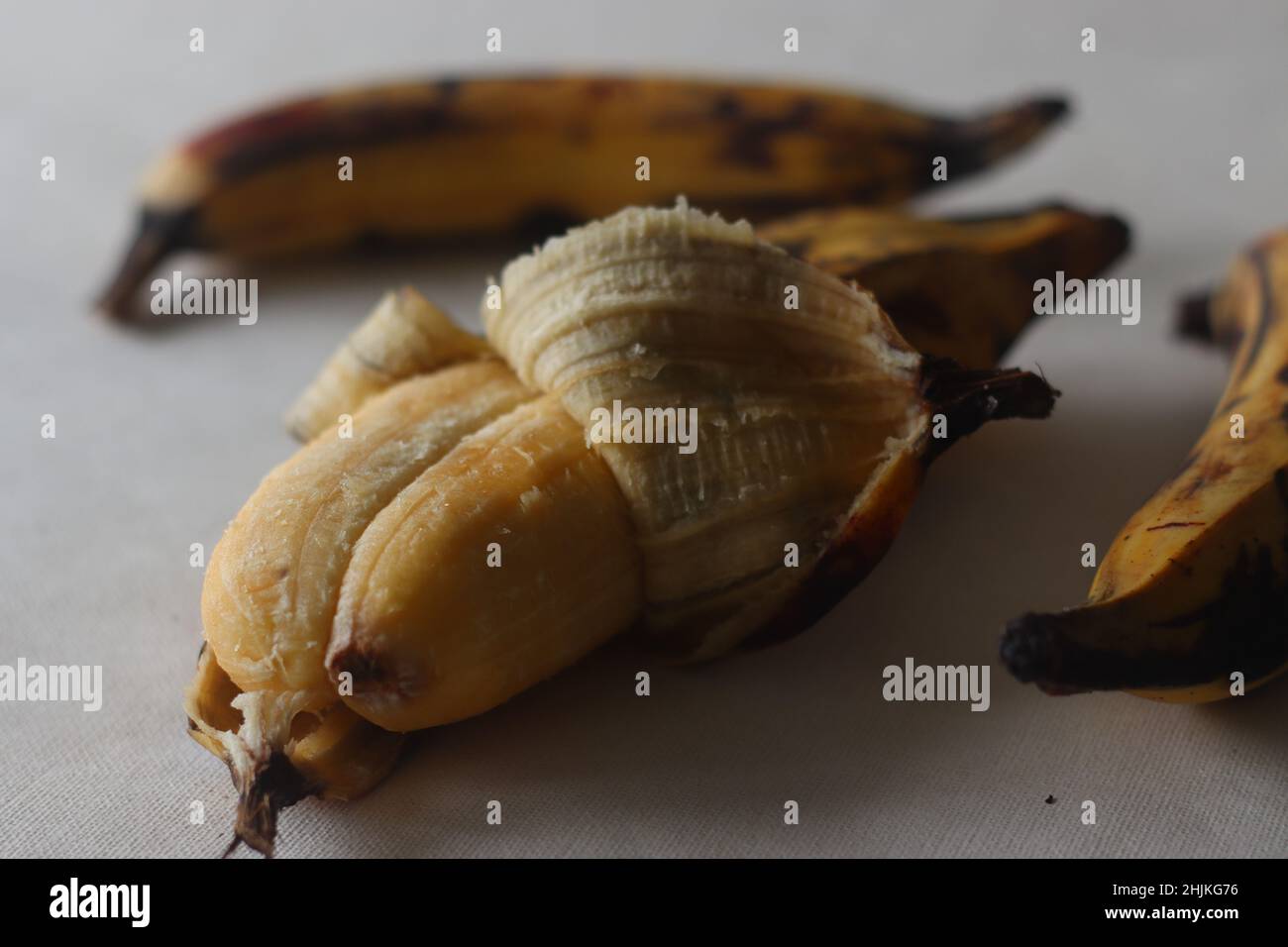 Twin Ripe plantain yellow in colour, ready to eat with skin half peeled ...