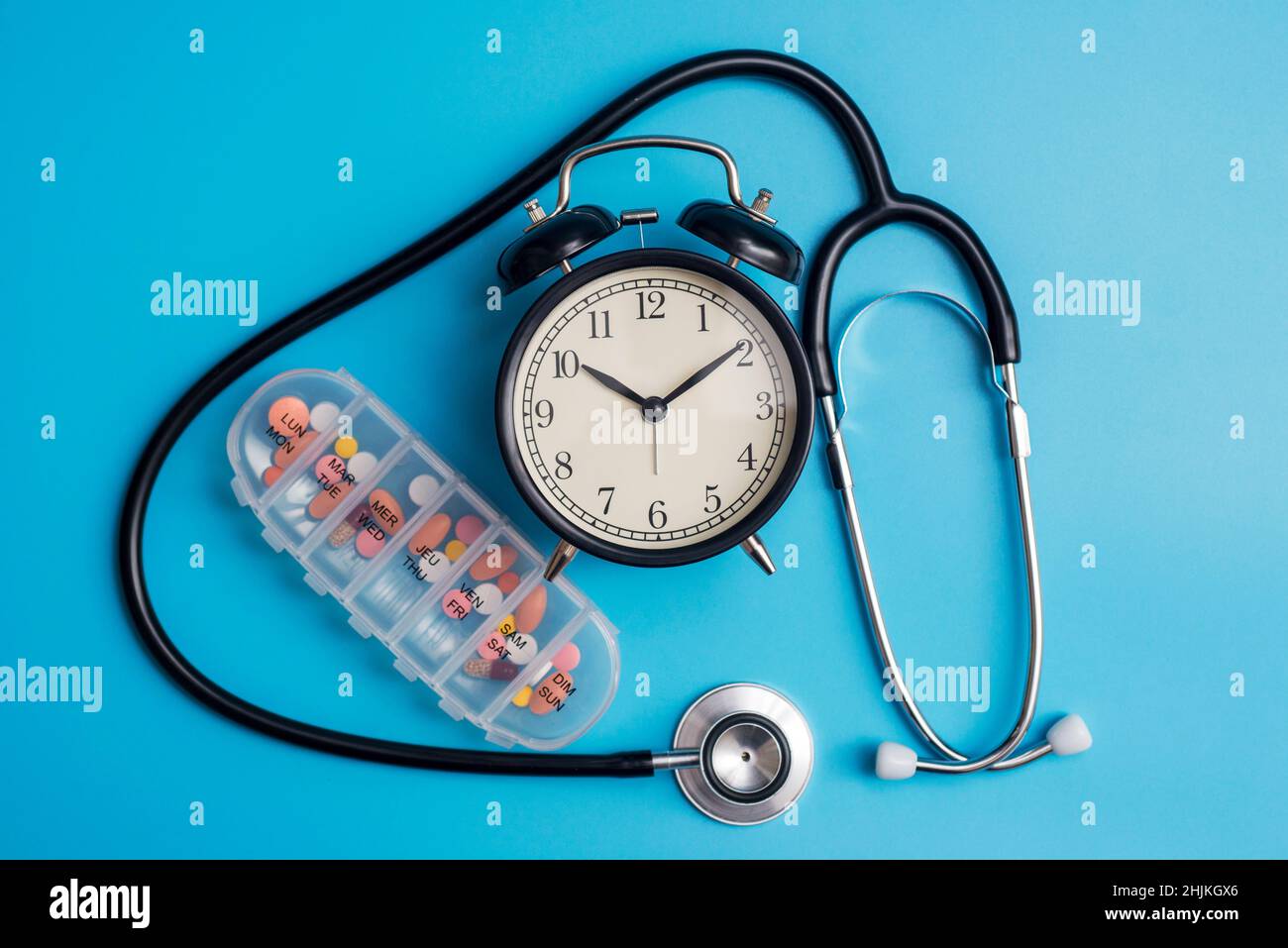 Composition with medical stethoscope, alarm clock and pills on a blue ...