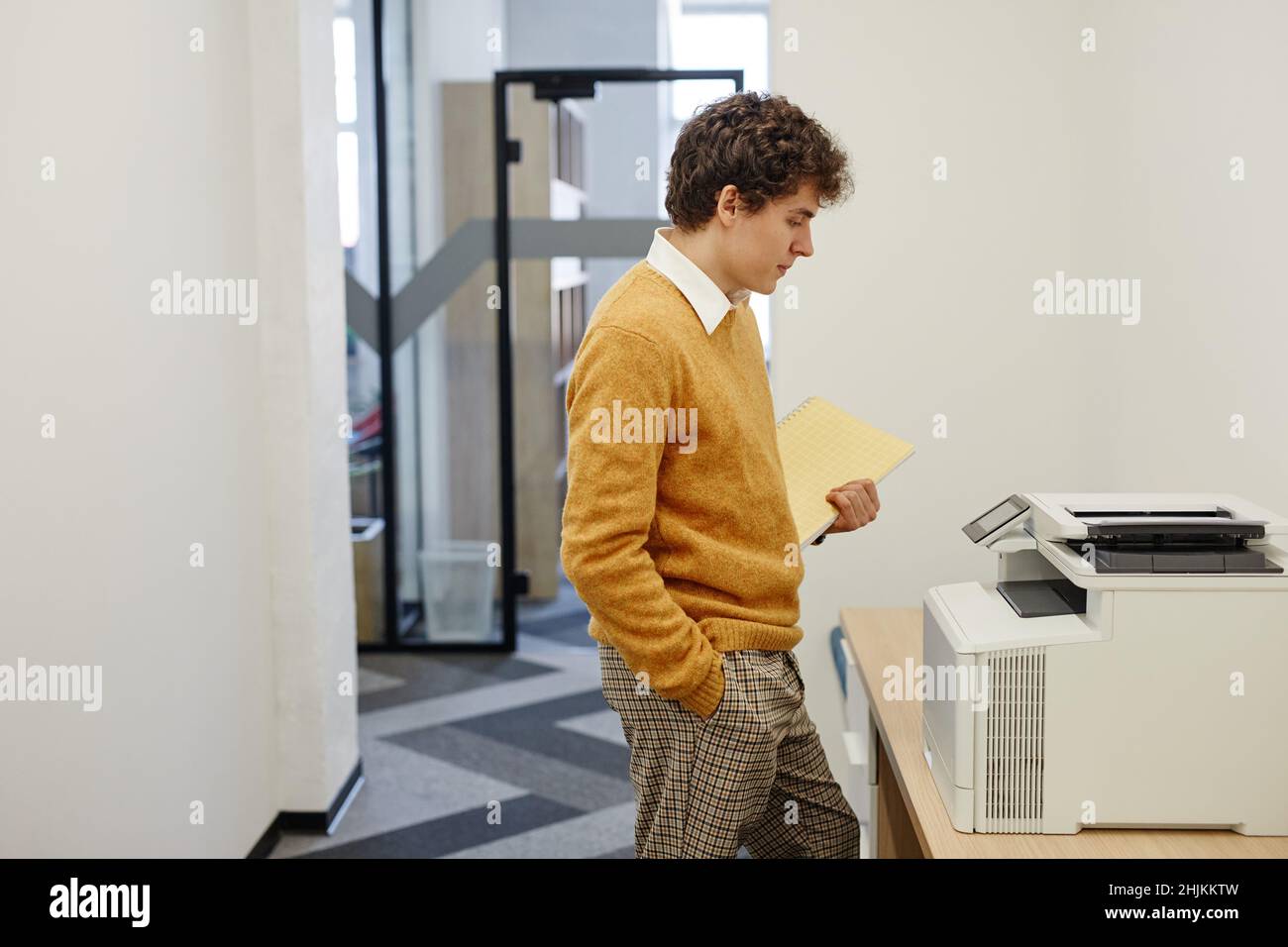 Side view portrait of young man using copying machine in office, copy ...