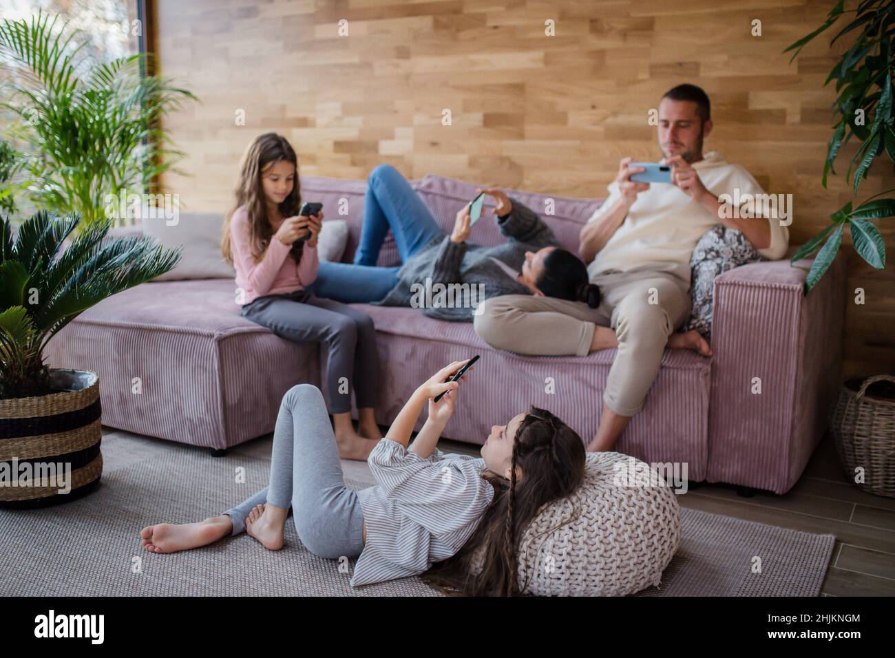 Family with two little daughters, everyone is using mobile phone in the ...