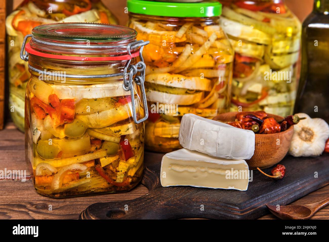 White cheese with herbs dipped in olive oil in small jar. Marinated ...