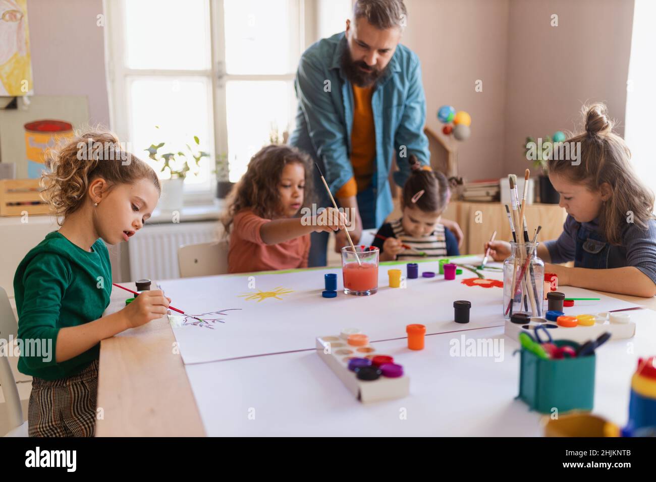 Group of little kids working on project with teacher during creative ...