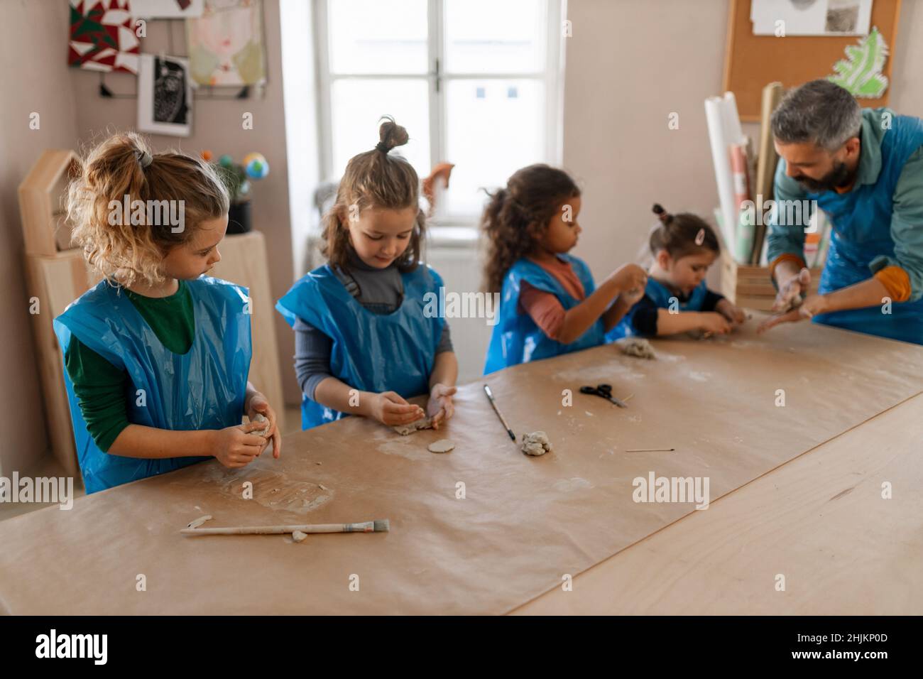 Group of little kids with teacher working with pottery clay during ...