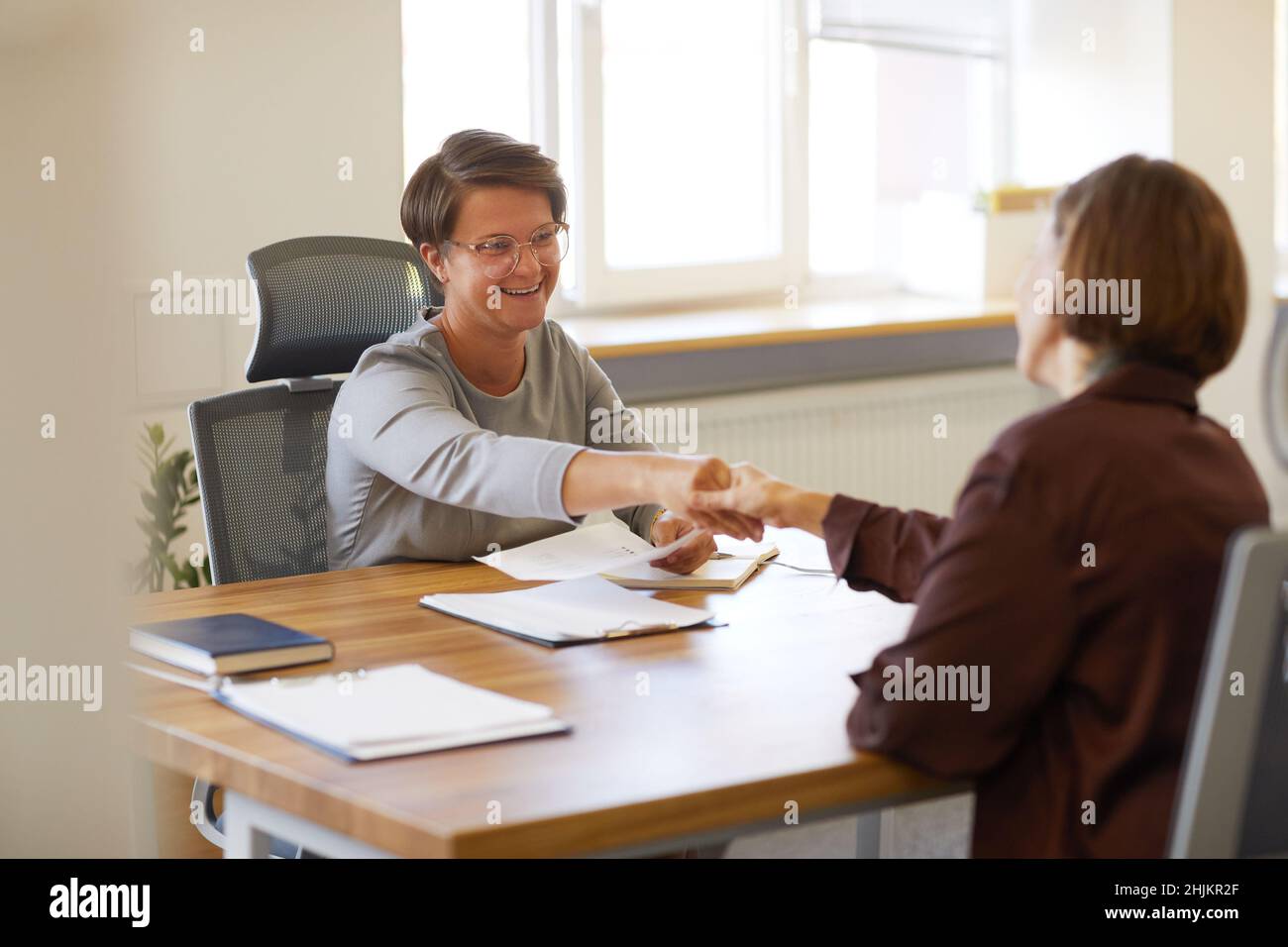 Portrait of female HR manager handing contract to young woman at job ...