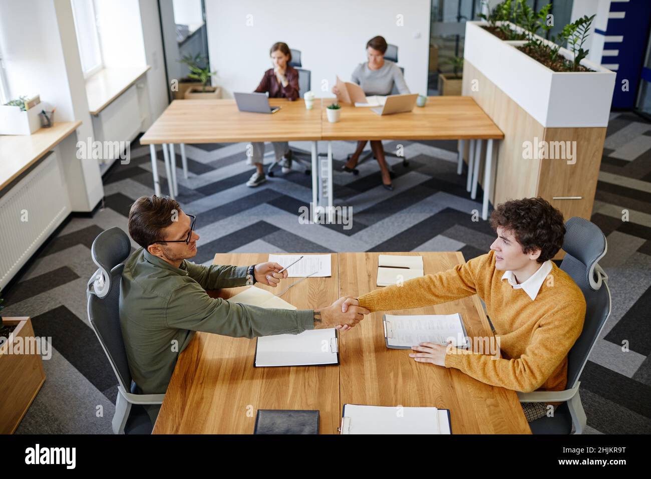 High angle portrait of HR manager shaking hands with young man at job ...
