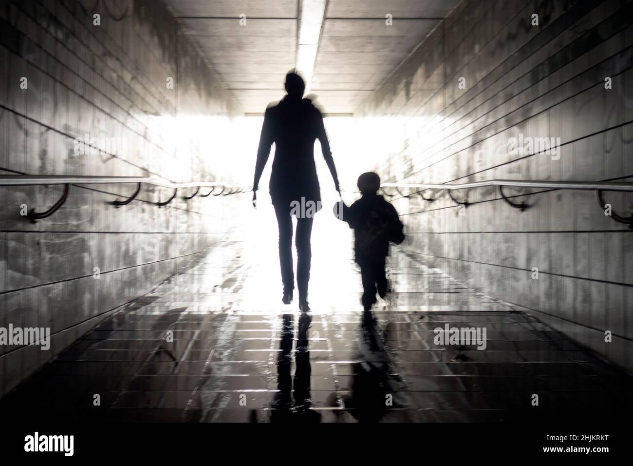 Mom and boy in tunnel. Keywords: from behind woman gray people dark ...