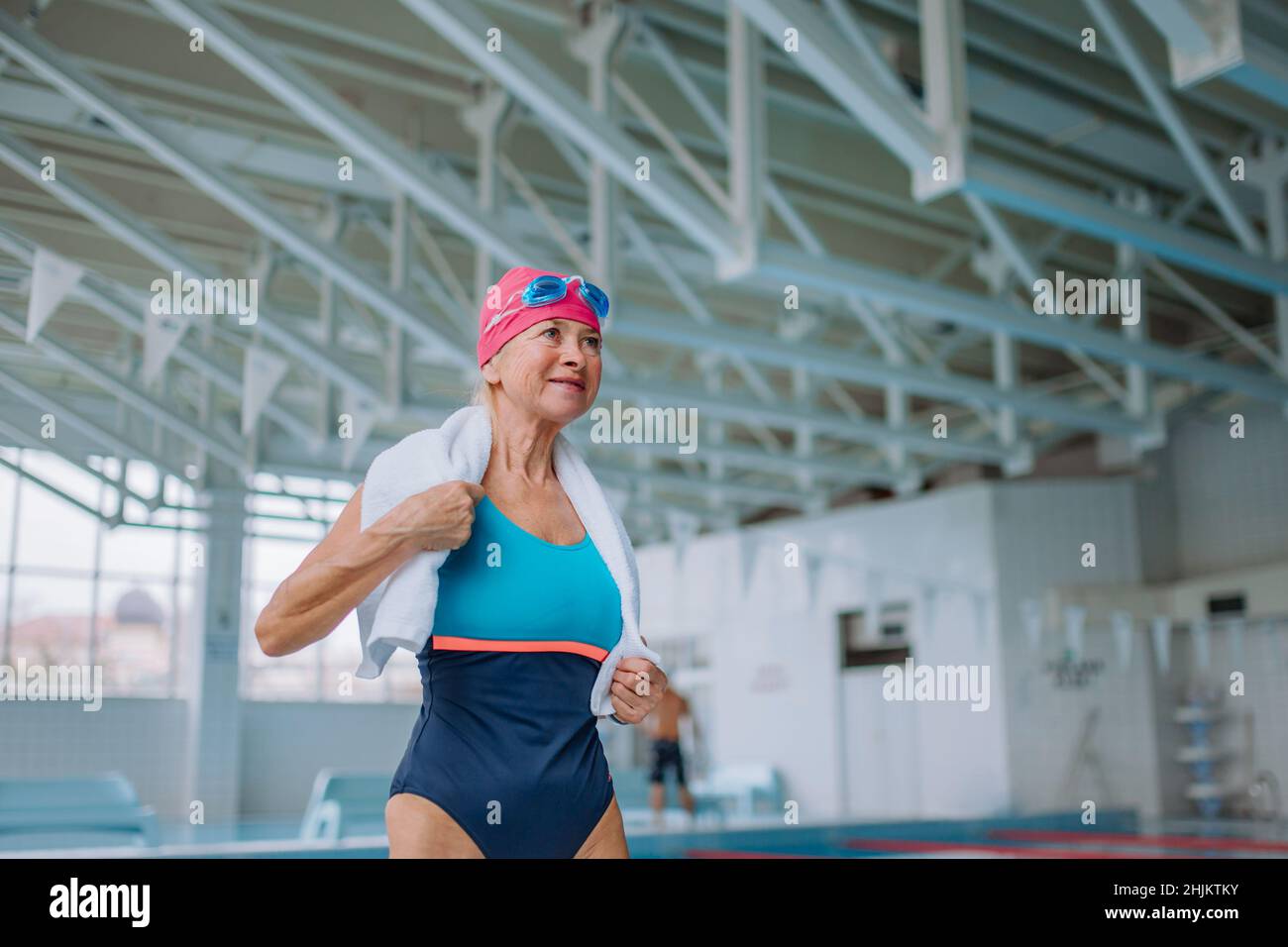 Low angle view of active senior woman preapring for swim in indoors ...