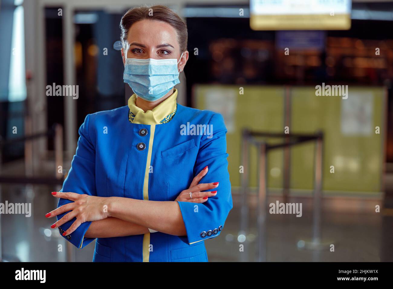 Flight attendant in protective face mask standing in airport terminal ...