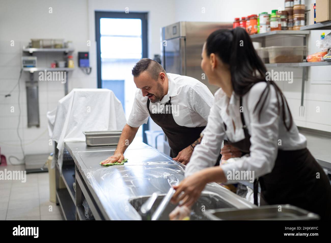 Chef and cook cleaning the workspace after doing dishes indoors in ...