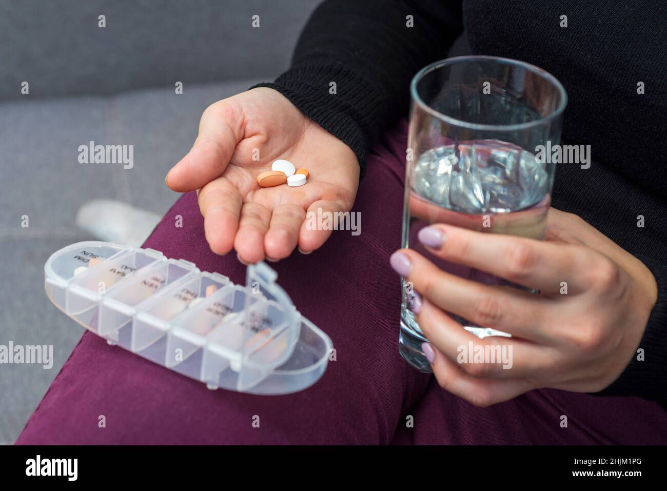 A female going to take tablets from pill box. A woman takes medicine ...