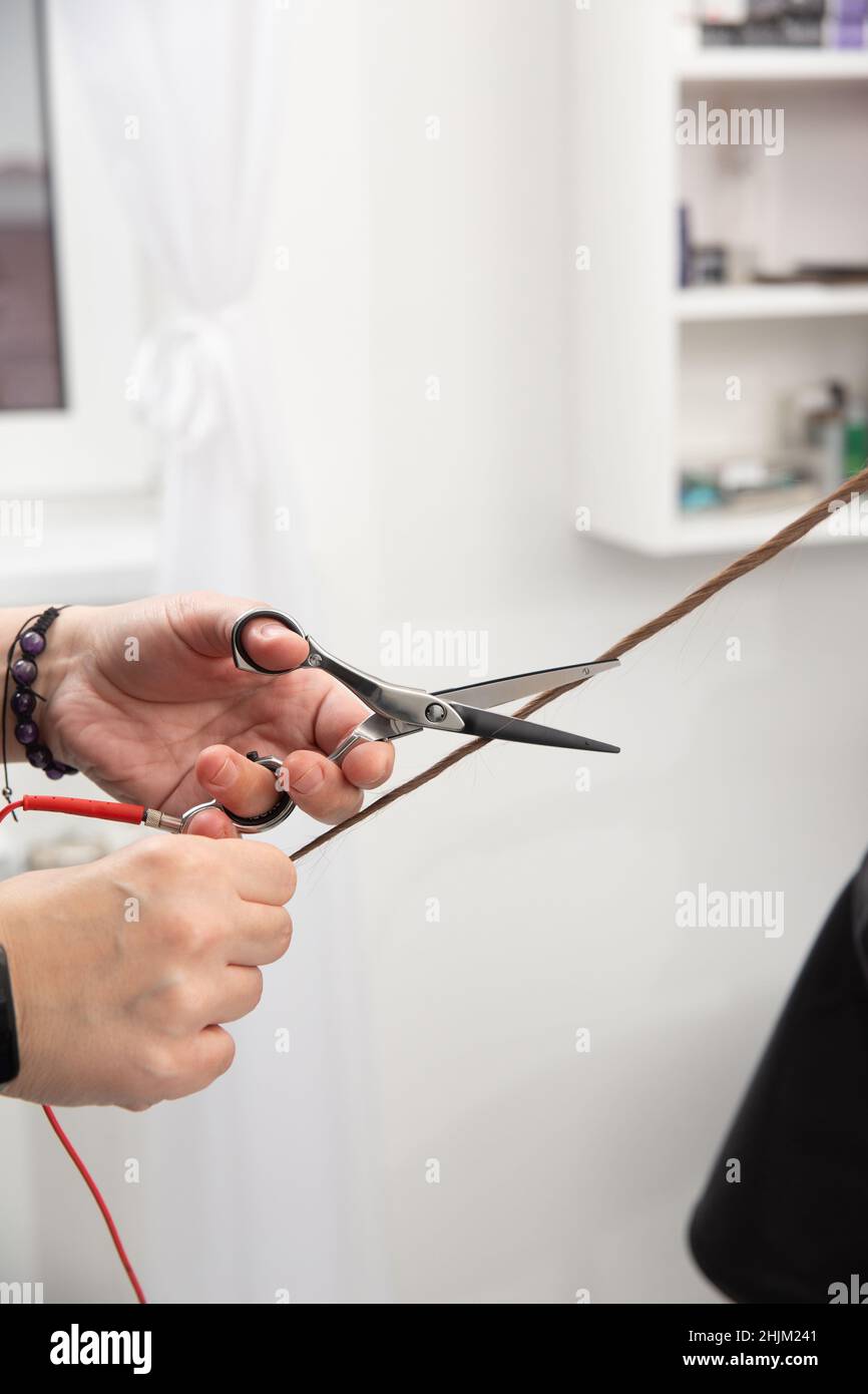 Professional hair stylist holding comb and hot thermal scissors cutting ...