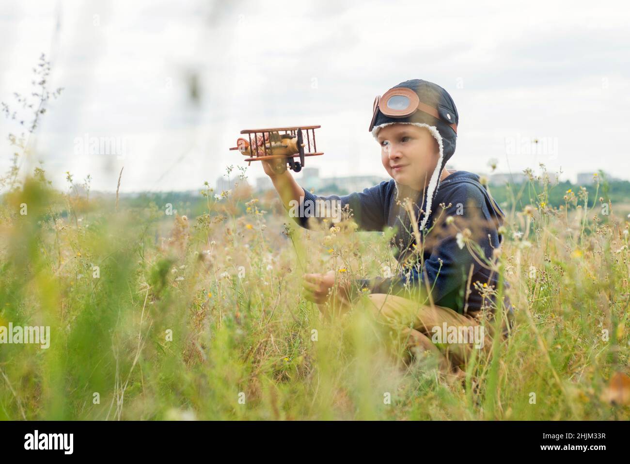 Happy child playing with a toy wooden plane outdoors. Little boy with ...