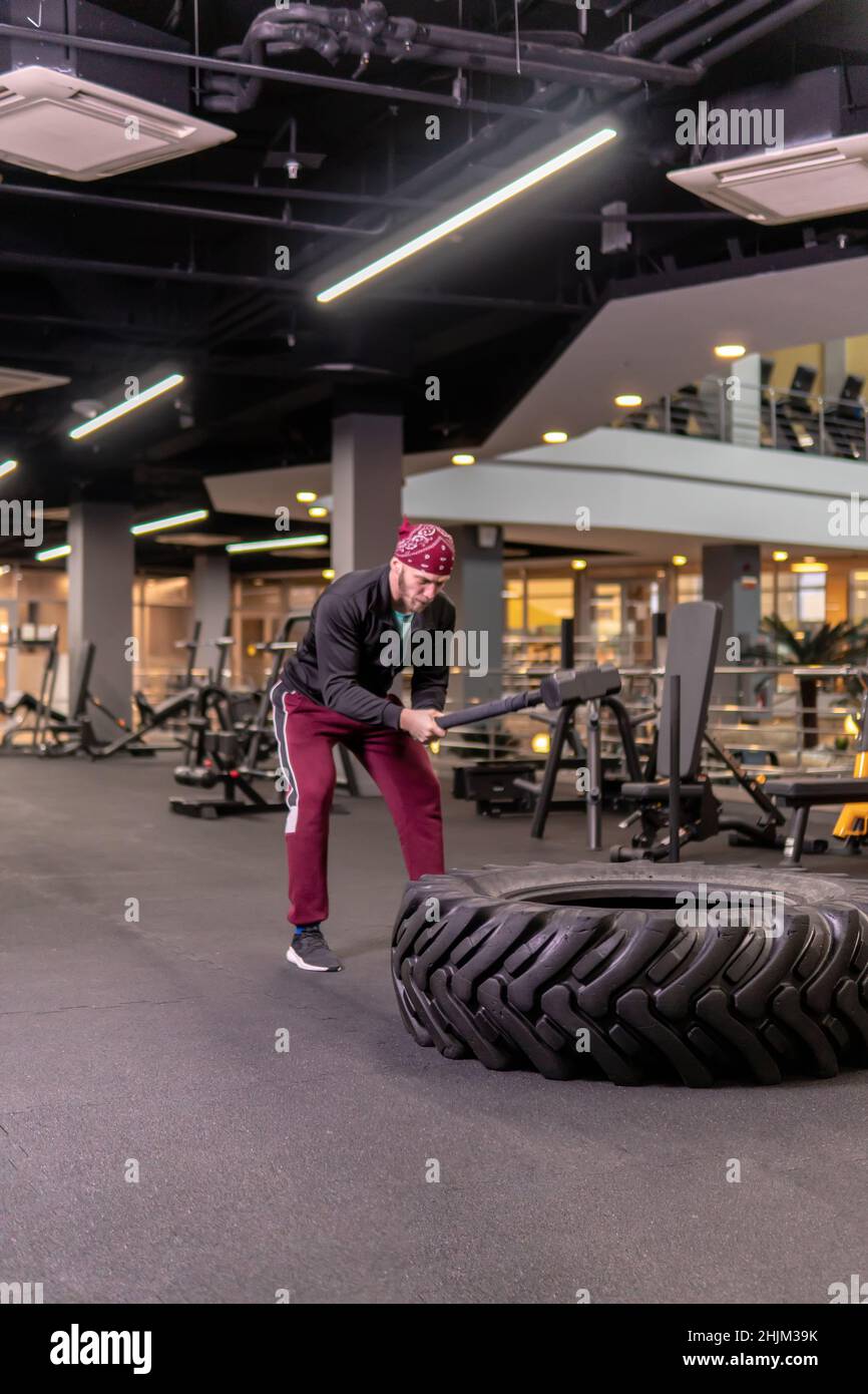 A man hits a sledgehammer wheel in fitness, the concept of a healthy ...