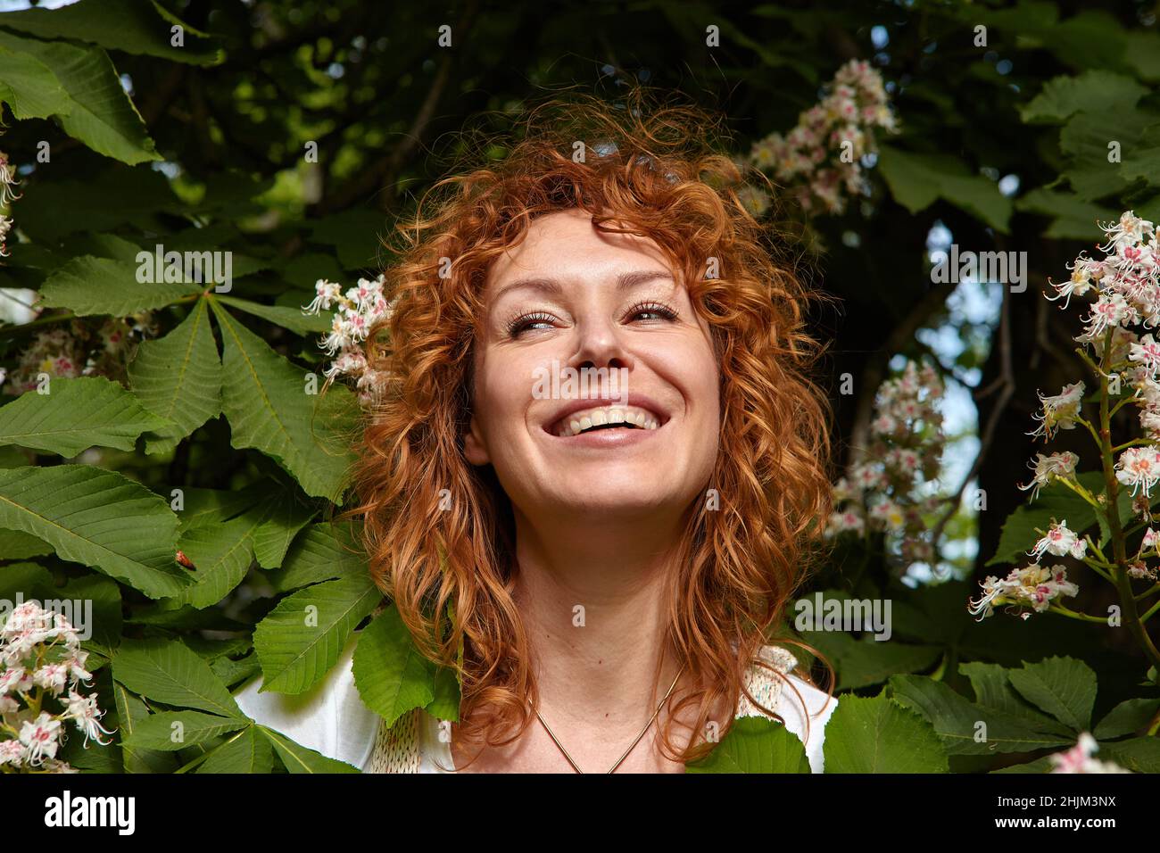 Portrait of beautiful red hair woman with beaming smile among the ...