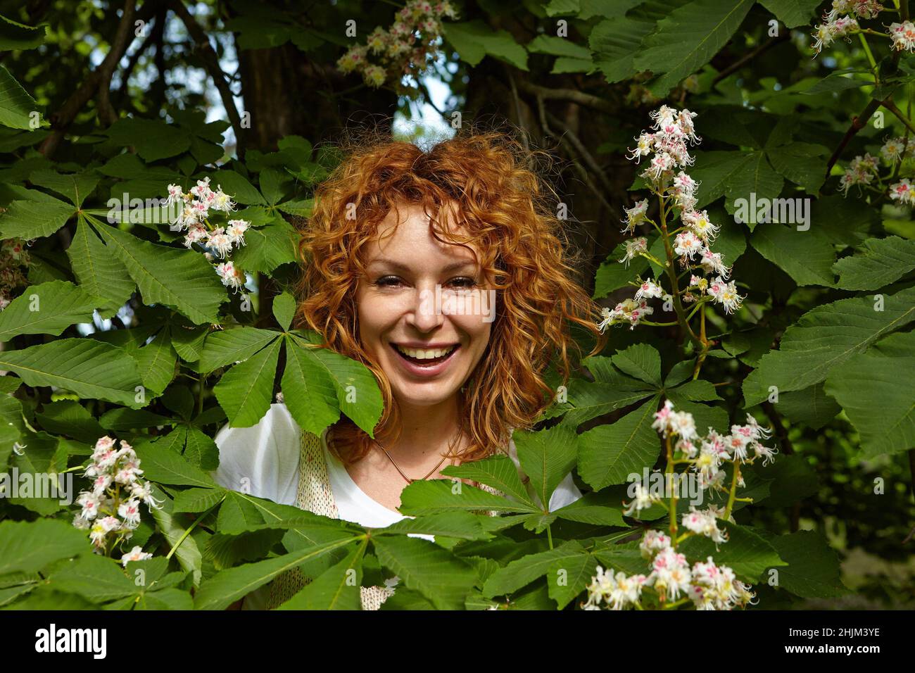 Portrait of beautiful red hair woman with beaming smile among the ...