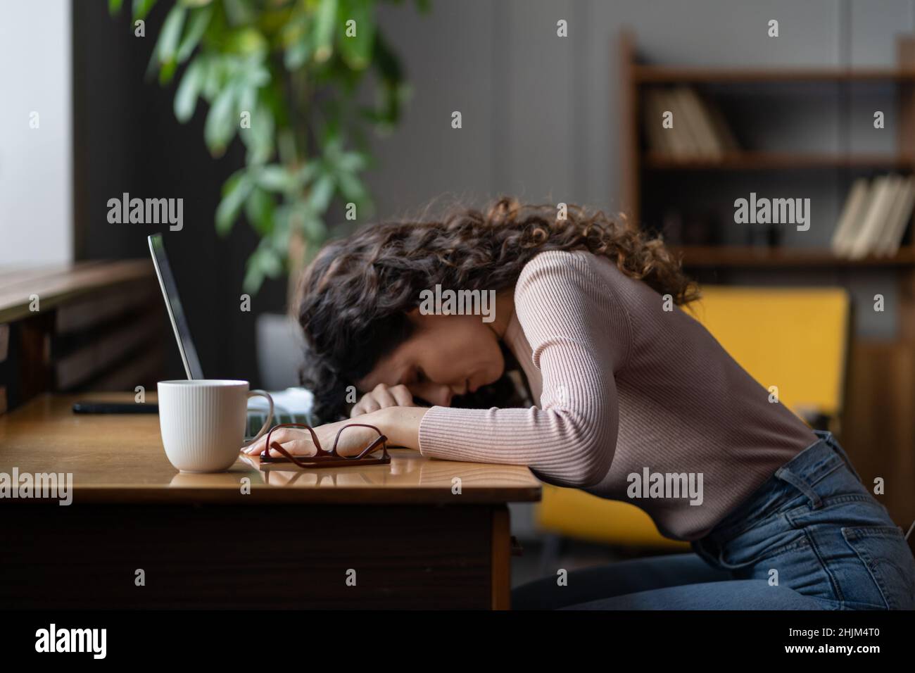 Overworked tired female freelancer or remote worker sleep on desk with ...