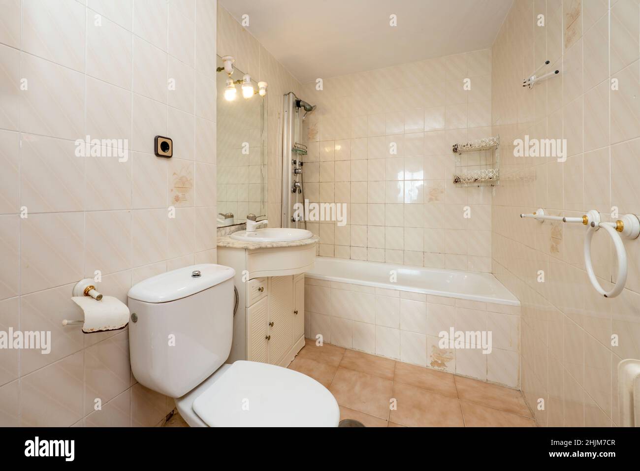 Conventional toilet with white furniture, cream-colored tiles and white ...