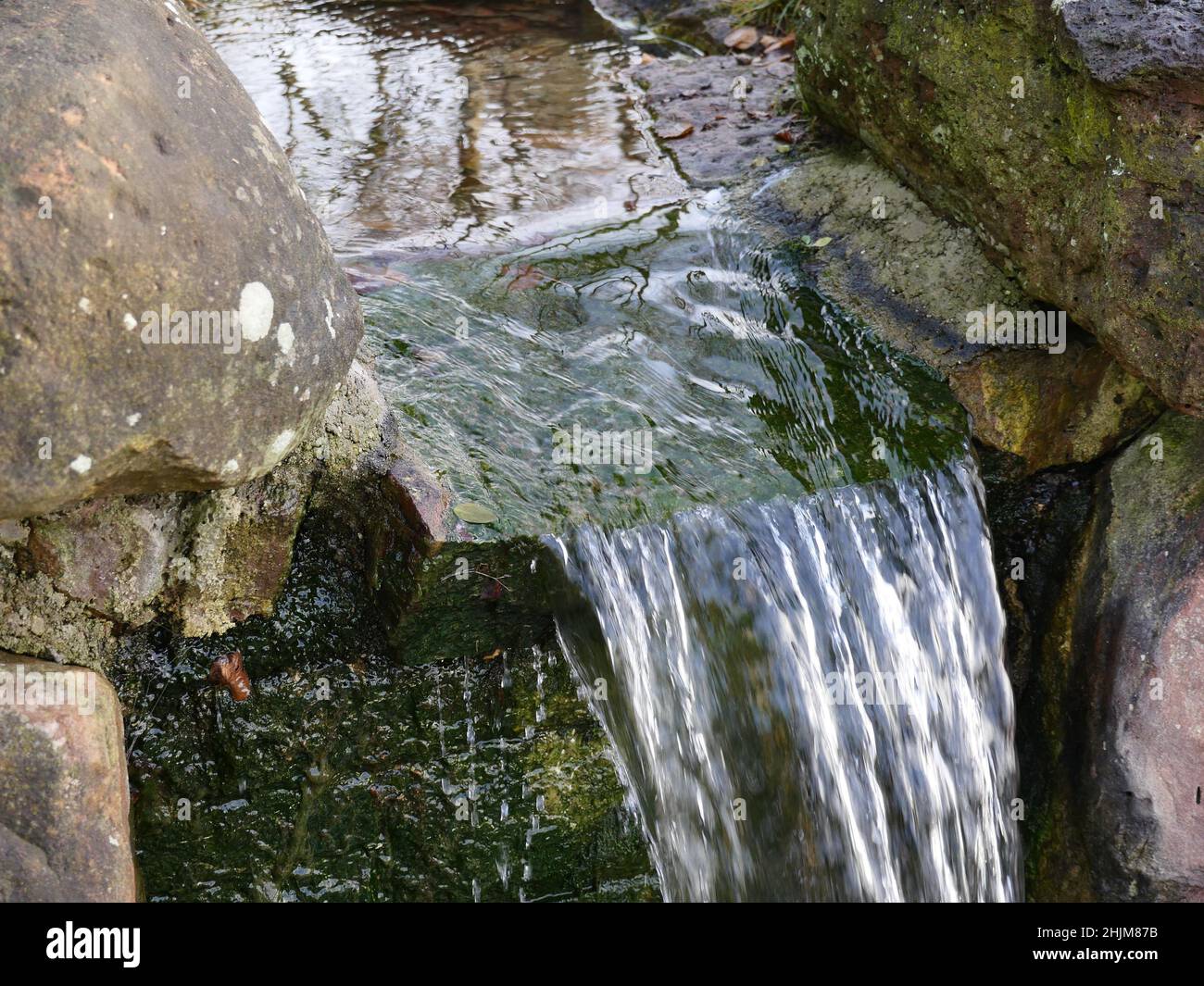 Stream between two boulders, a miniature waterfall Stock Photo - Alamy