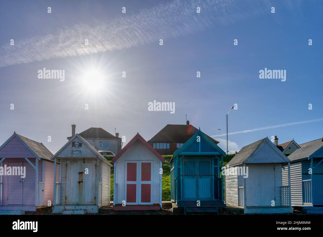 A row of English traditional beach huts, painted in vibrant pastel ...