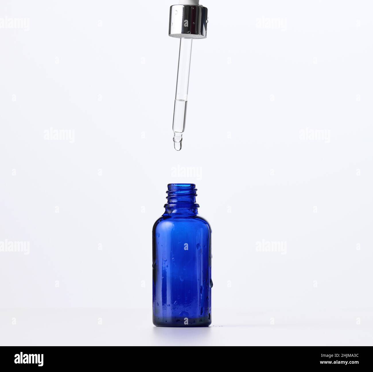 essential oil falling from the amber glass dropper. Blue bottle of ...