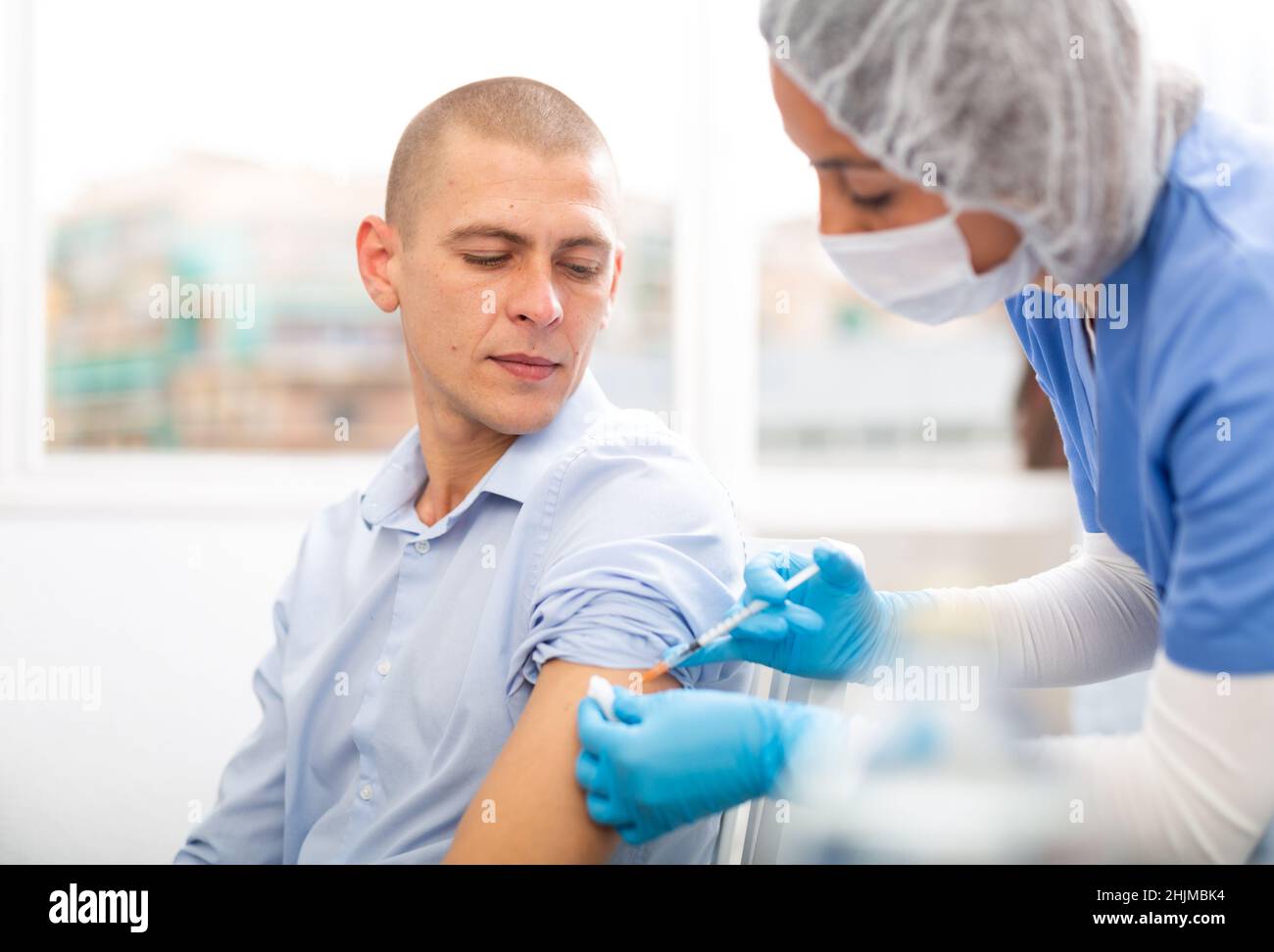 Professional nurse giving vaccine injection to man Stock Photo - Alamy