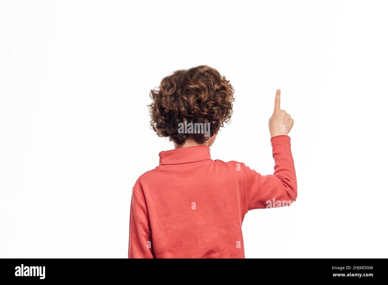 Boy pointing finger up to show something while standing on an isolated ...