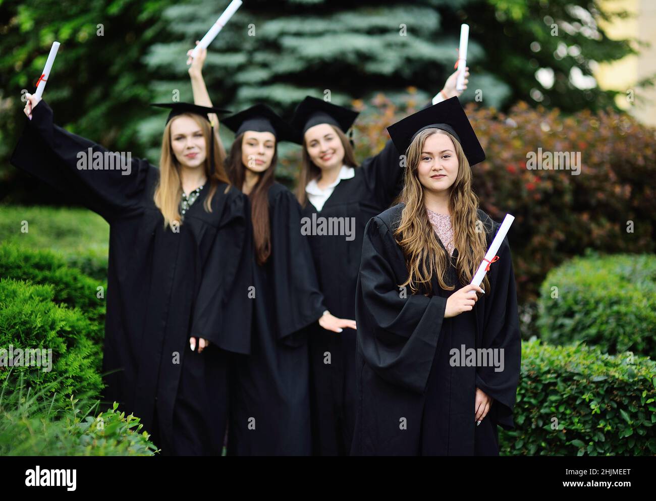 pretty young girl is a college graduate student in a black robe smiling ...