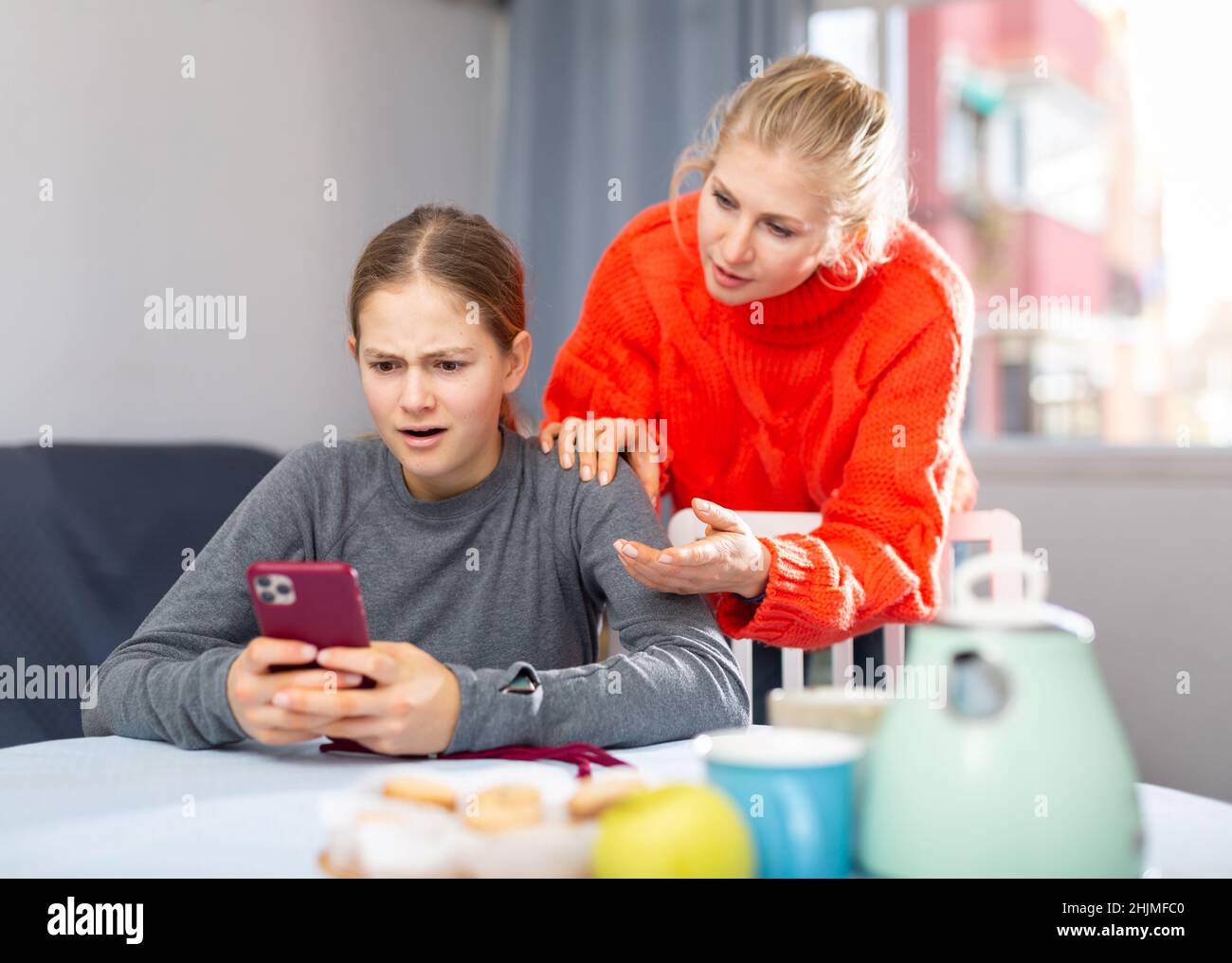 Girl sitting with phone, ignoring mother Stock Photo - Alamy