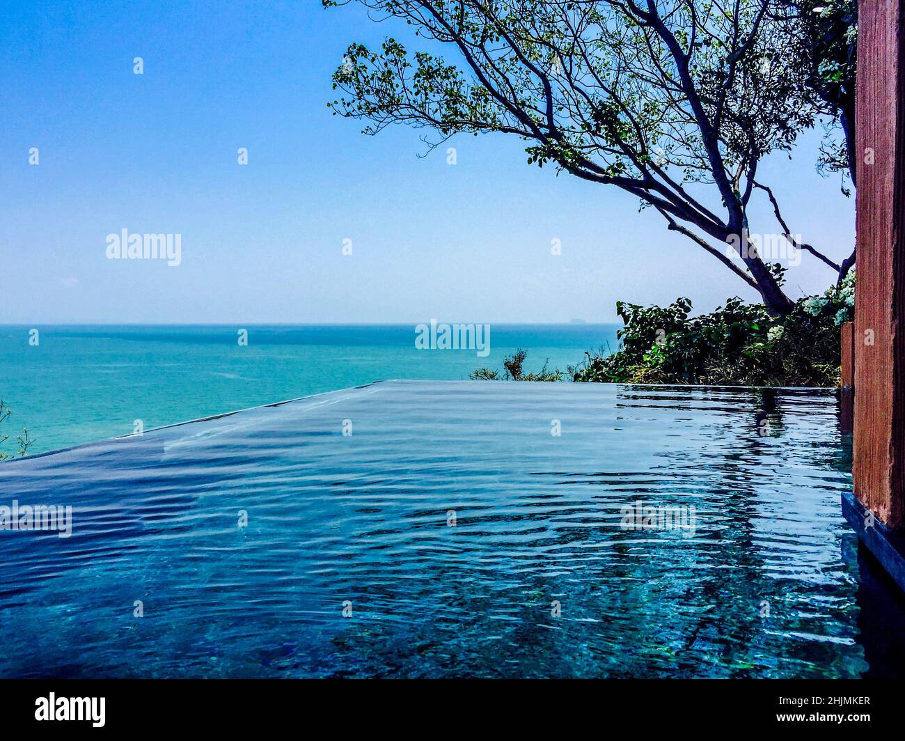 Blue water infinity pool overlooking the blue ocean Stock Photo - Alamy