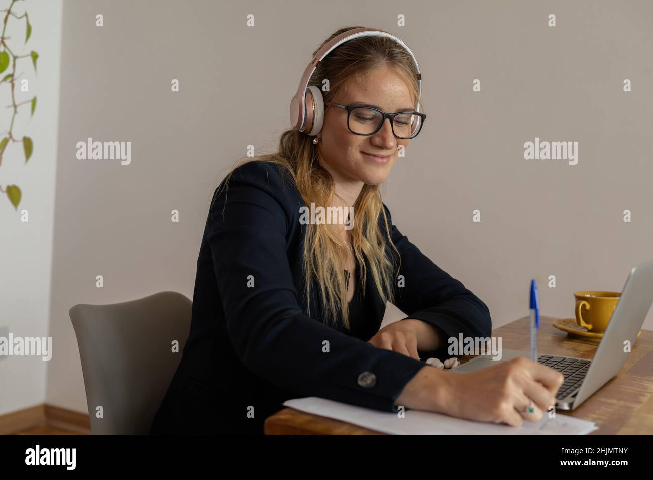Young woman working at home with laptop and papers on desk and ...