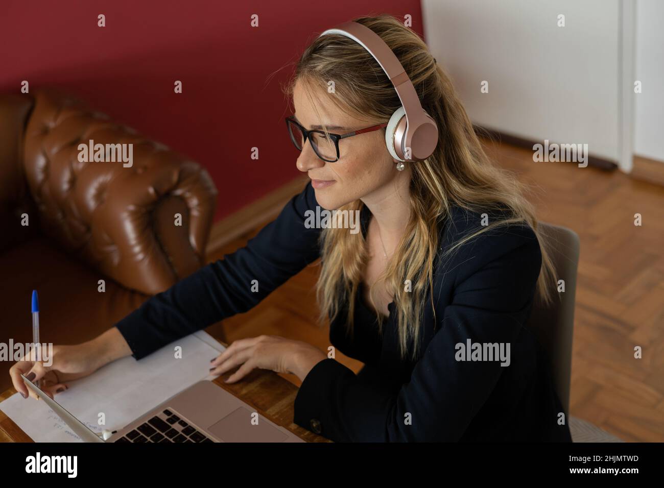 Young woman working at home with laptop and papers on desk and ...