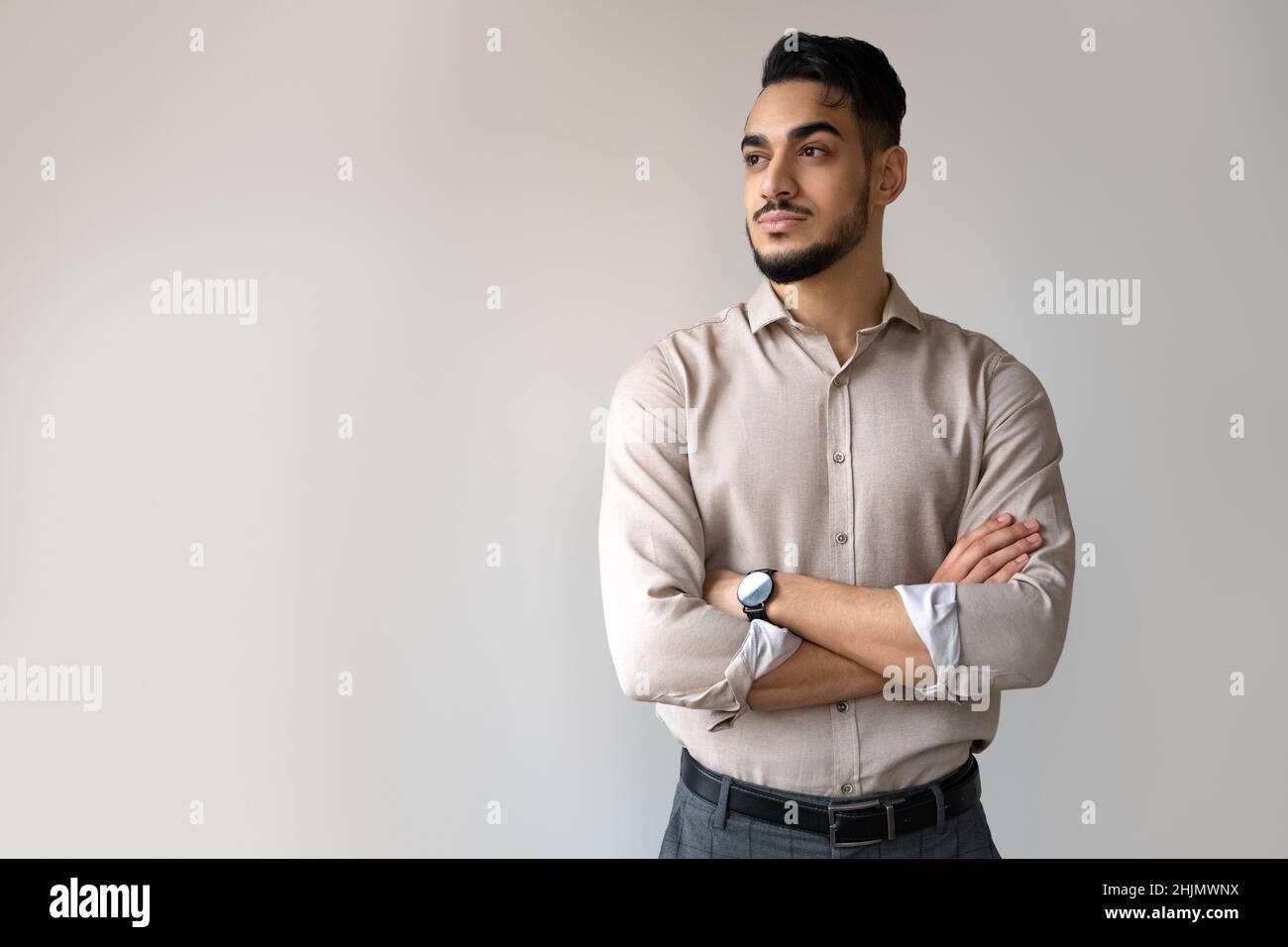 Studio portrait of serious indian man looking aside standing over grey ...