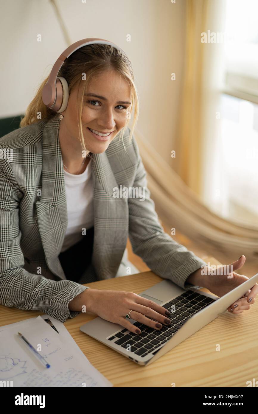 Young woman working at home with laptop and papers on desk and ...