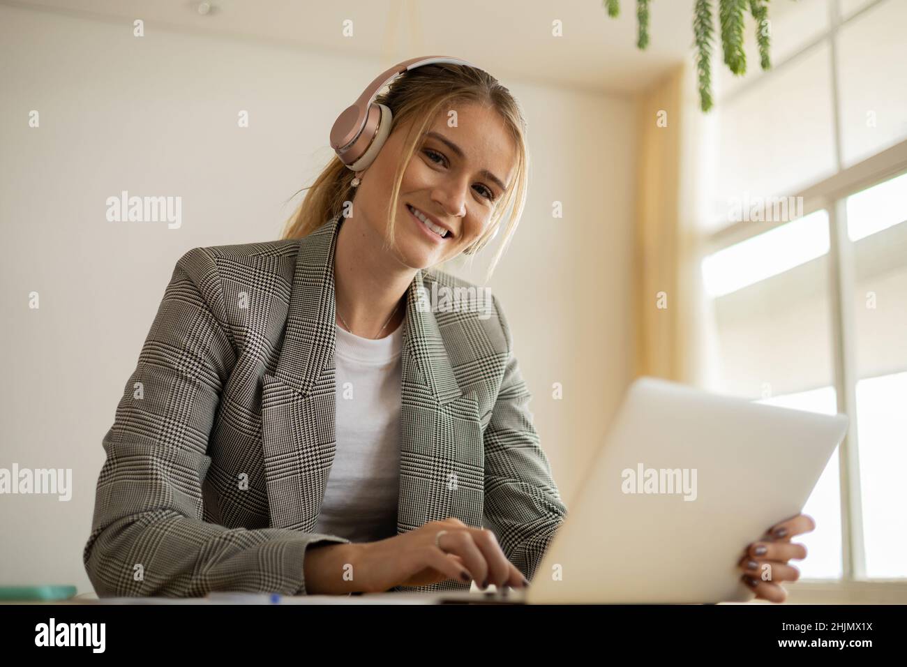 Young woman working at home with laptop and papers on desk and ...