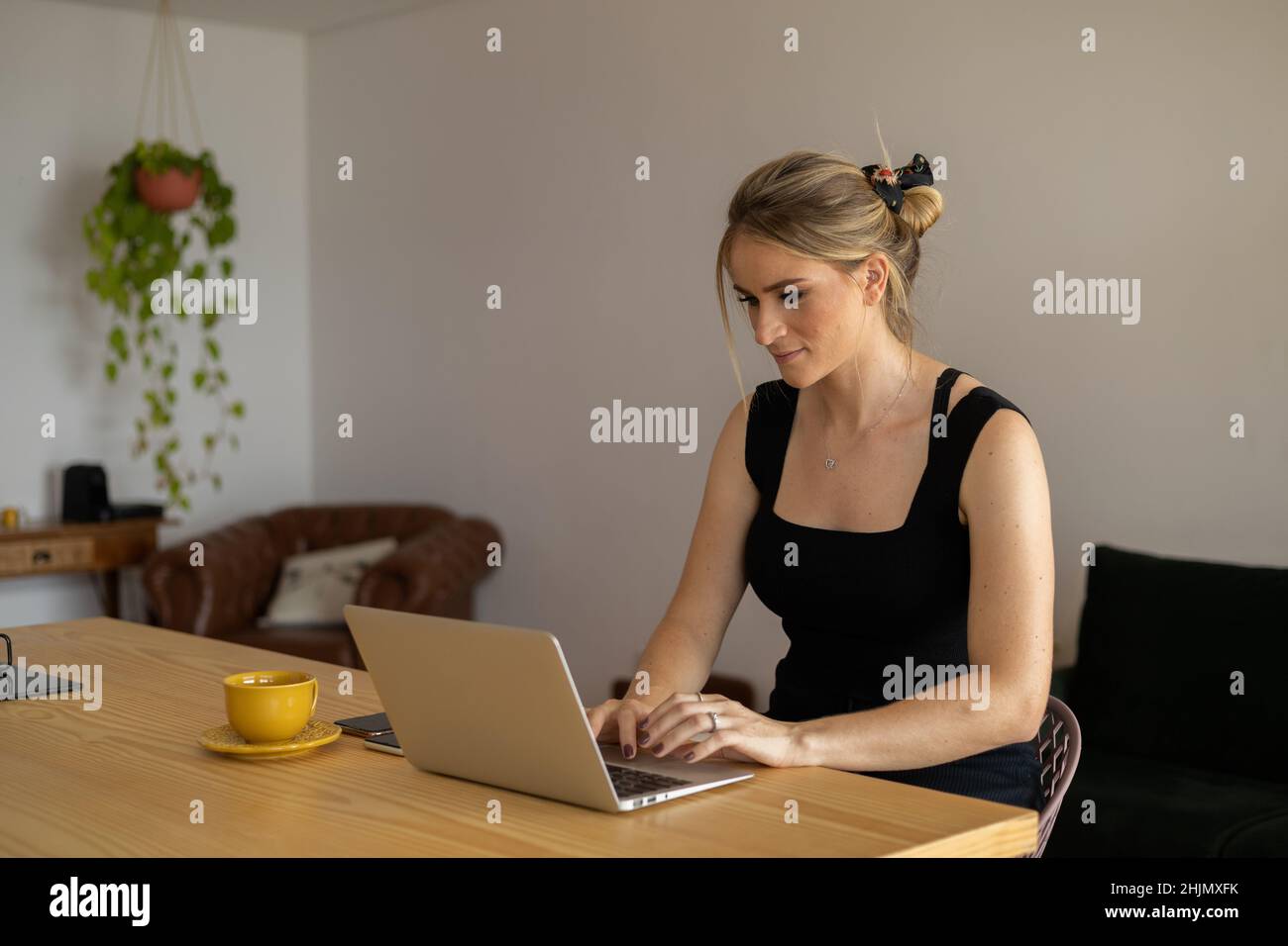 Young woman working at home in her kitchen with laptop and papers on ...