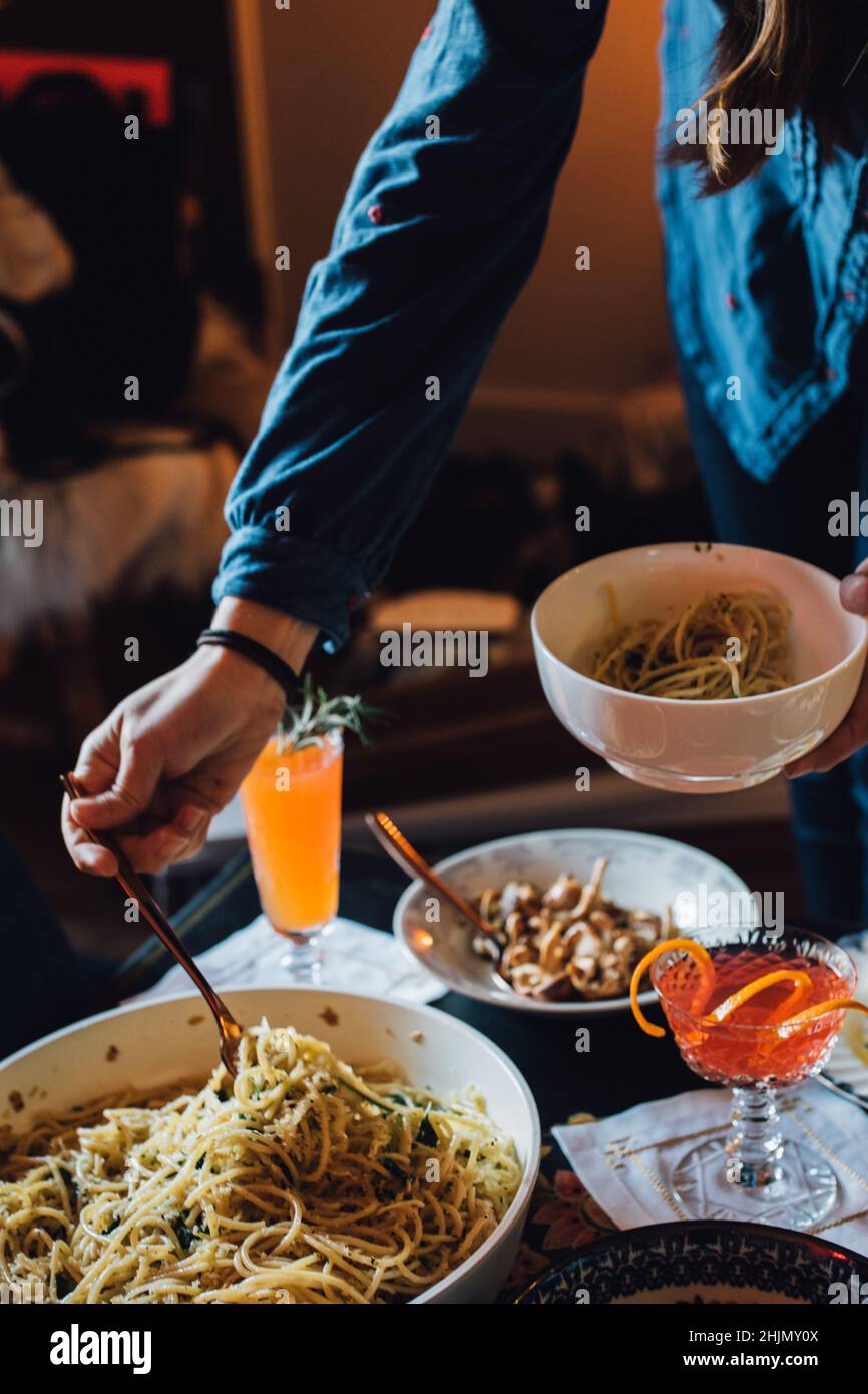 woman serving herself spaghetti noodles over table full of food, dinner ...