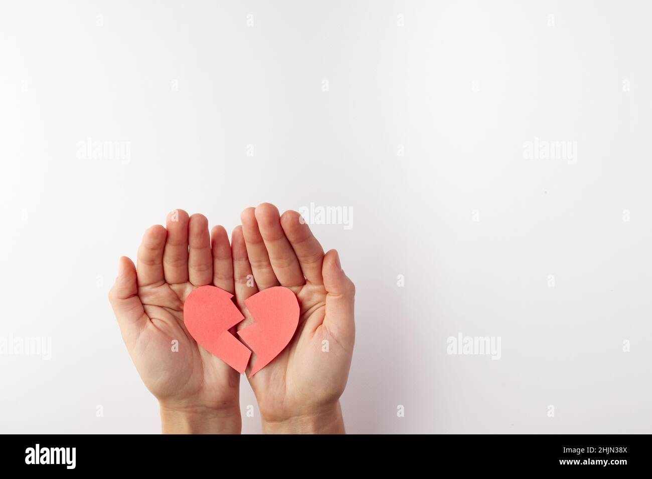 Broken heart and hands on a white background. Top view. Copy space ...