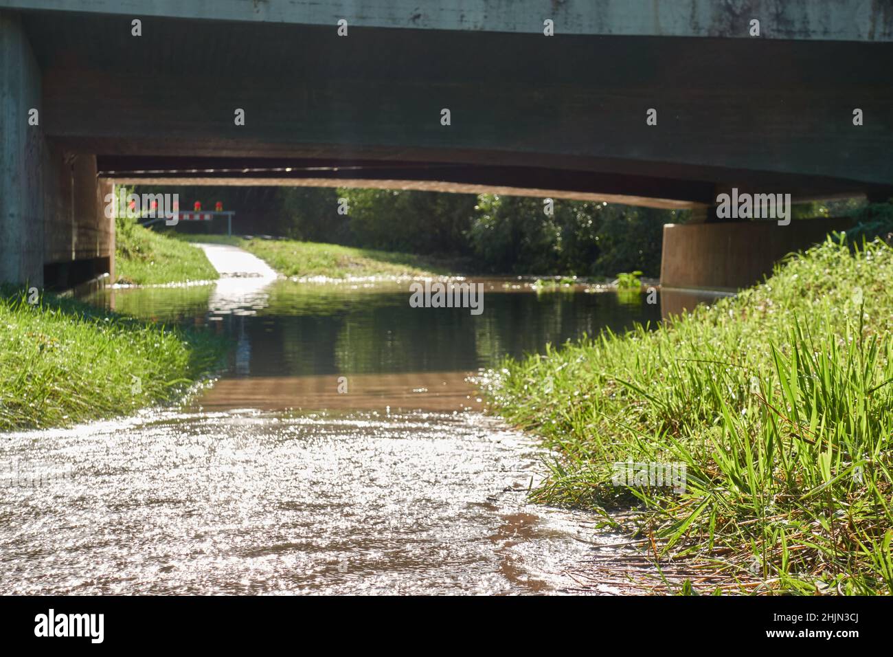 Flooded road after heavy rain. Water overflows the river bank and backs ...