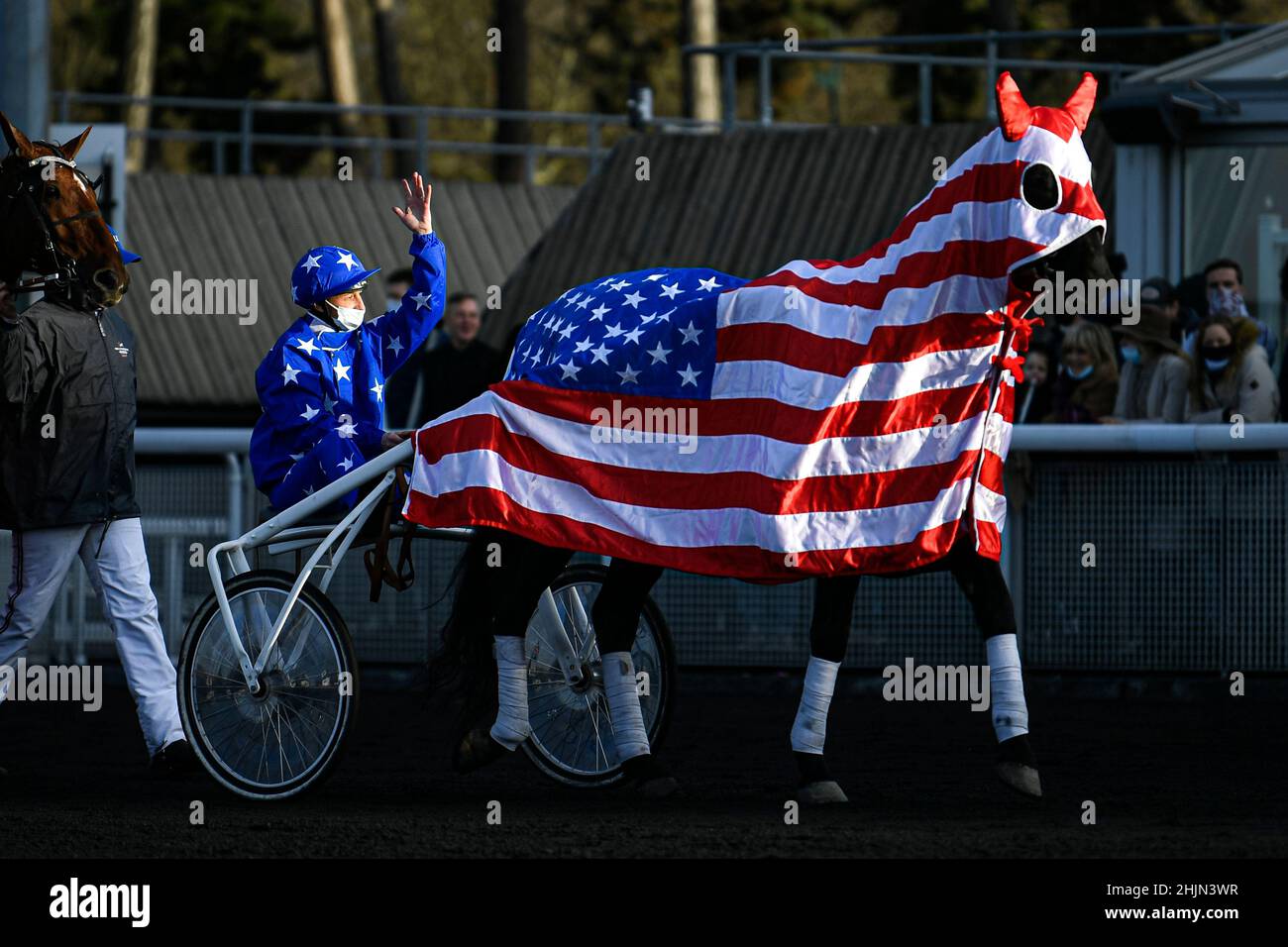 A jockey/driver parades with an American flag (USA) worn by the horse ...