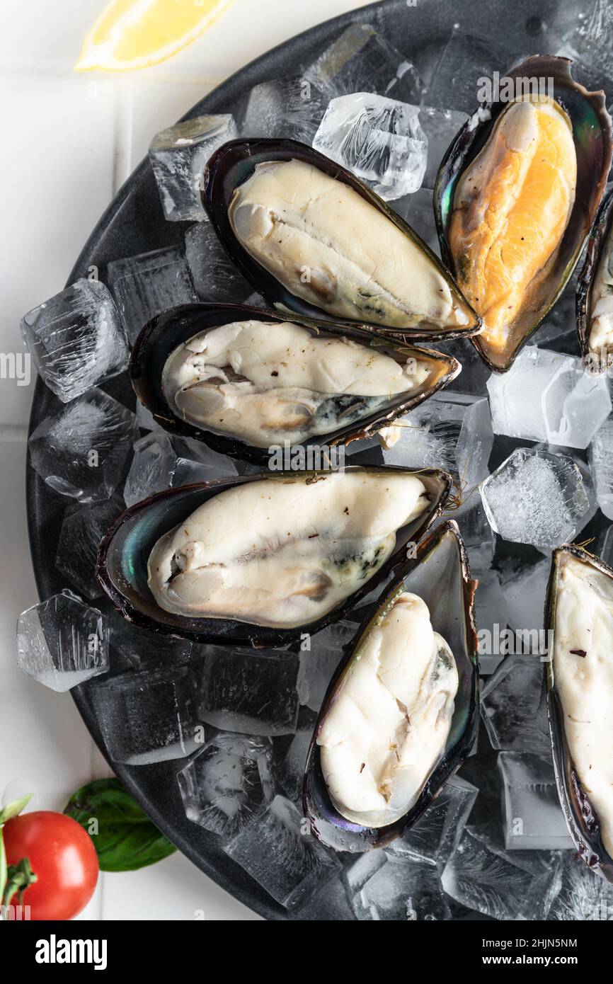 selective focus. raw mussels in the sink spread out on ice on a plate ...