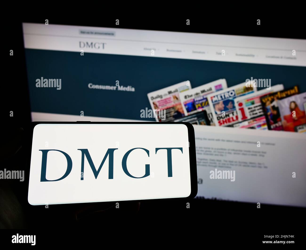 Person holding smartphone with logo of company Daily Mail and General Trust plc (DMGT) on screen ...