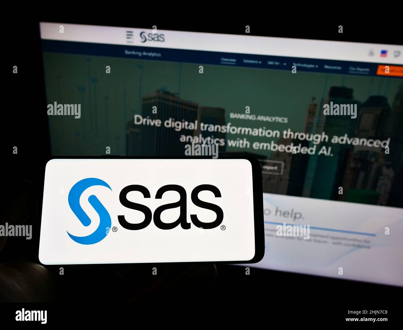 Person holding mobile phone with logo of US analytics software company ...