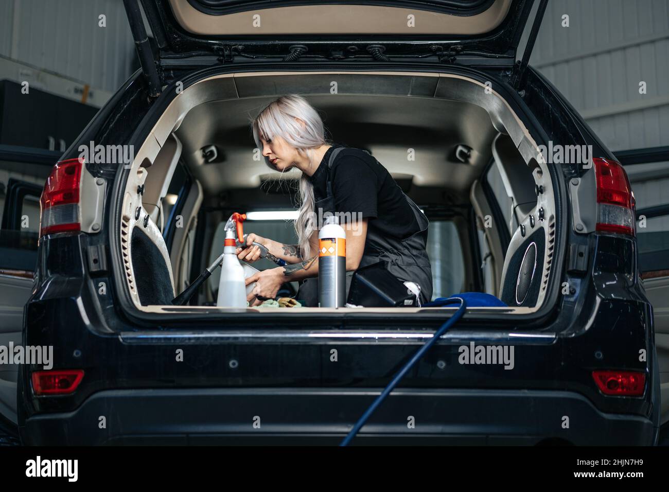 Woman cleaning car salon with polishing spray in car detailing service ...