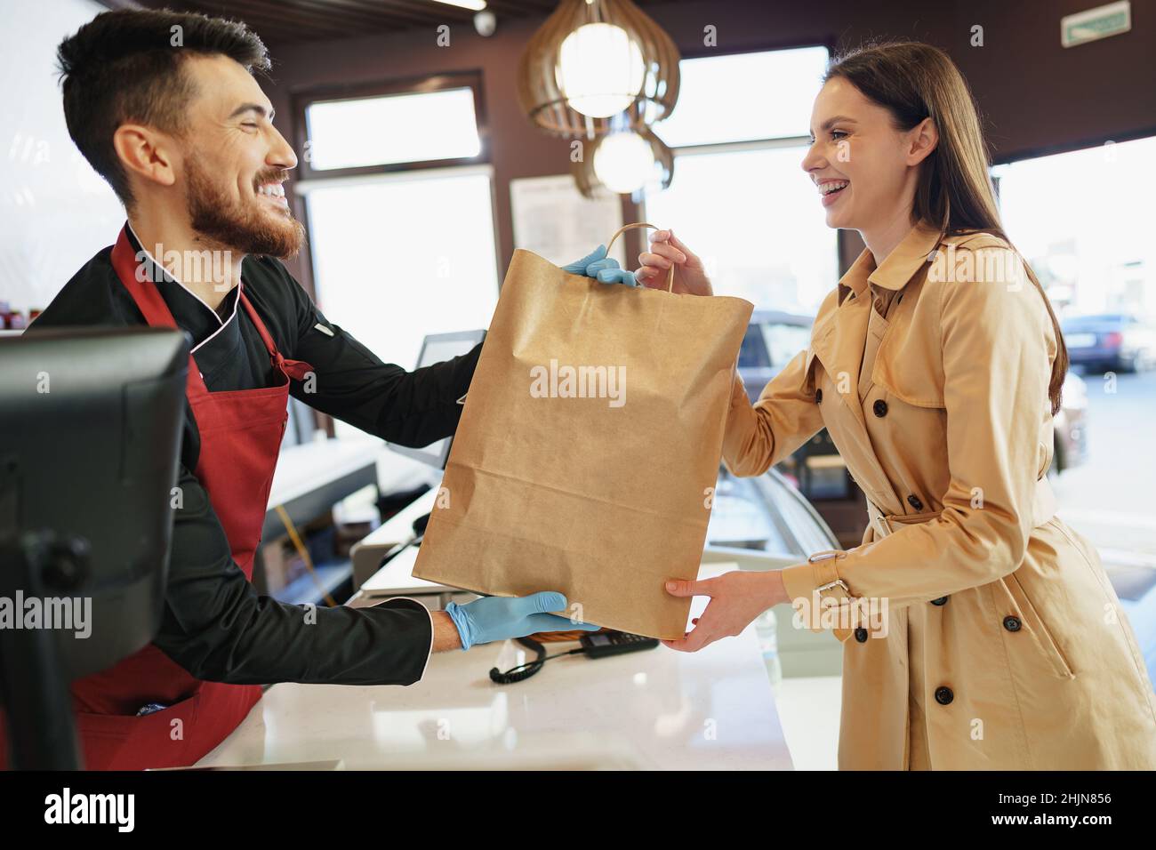 Shop assistant handling shopping bag to female customer in grocery ...