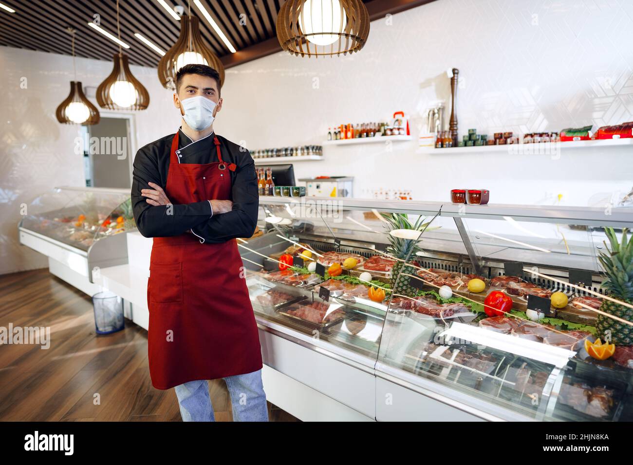 Portrait of a young man shopkeeper standing by meat stall in ...