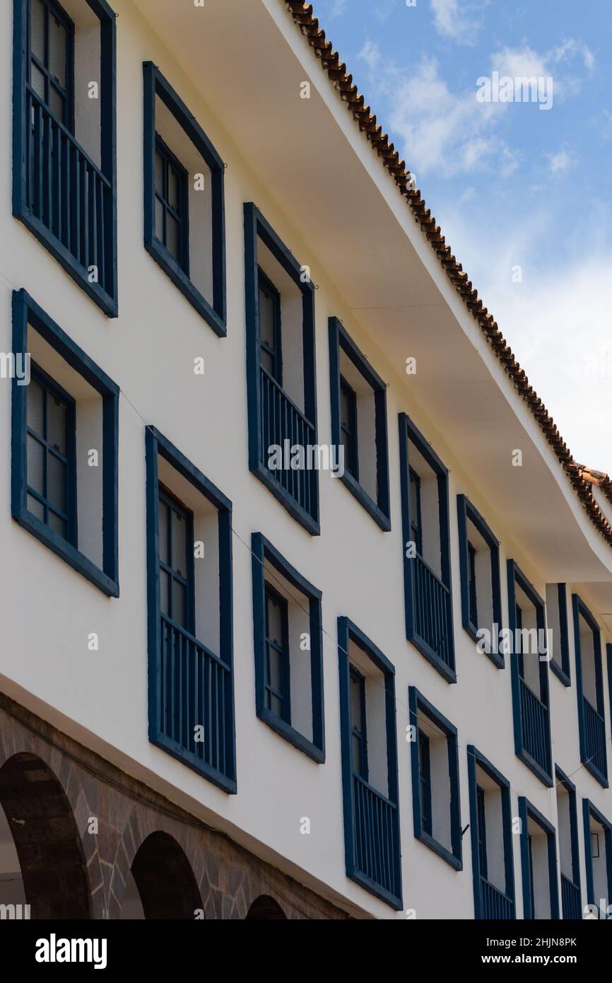 Side view of a modern building with blue metal windows against a cloudy ...
