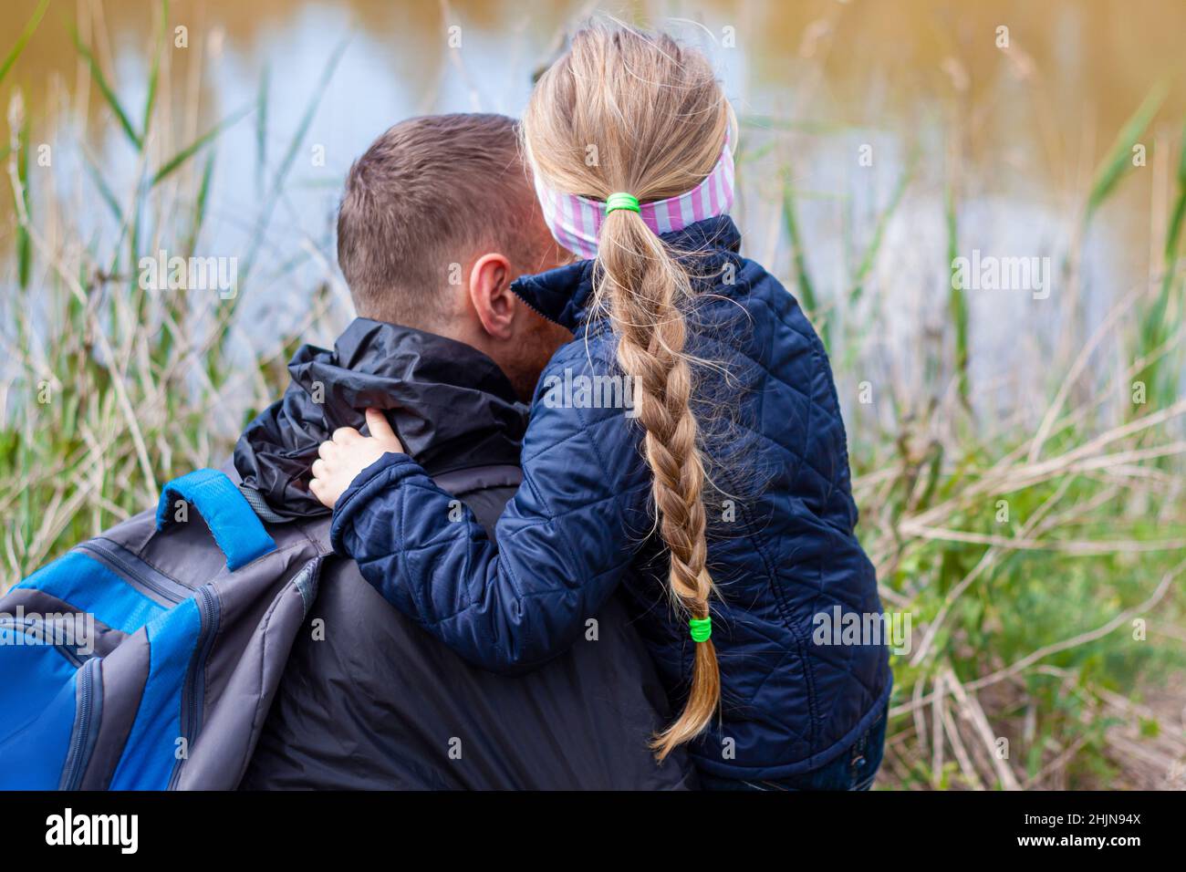 Father and daughter hugging sitting by the lake with nature lanscape ...