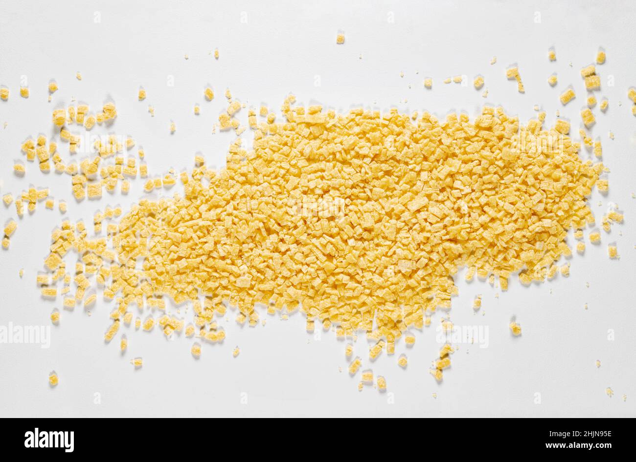 Small flat squares egg pasta called grattini on white background,yellow ...