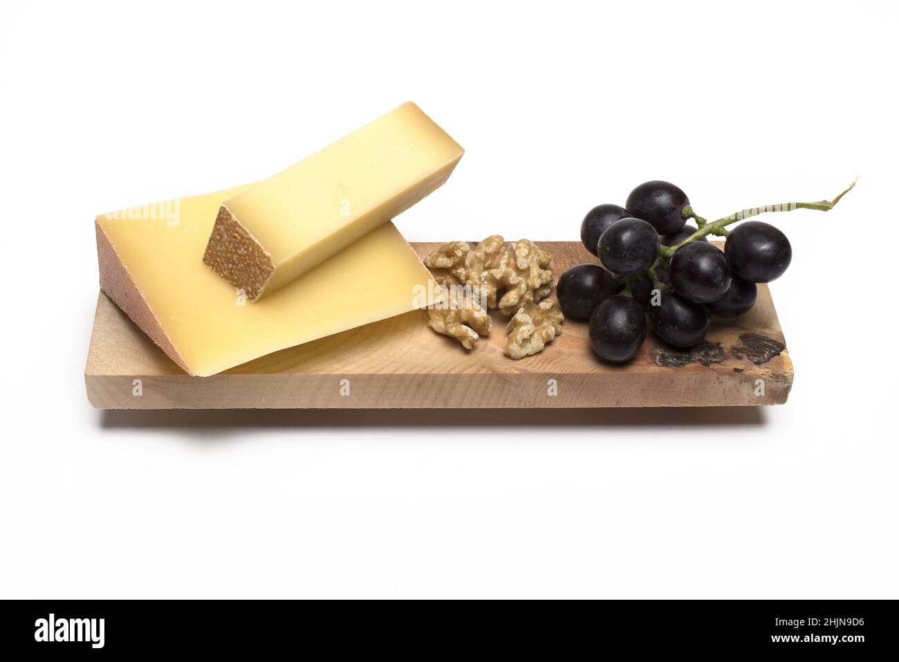 wedge and block of cheese traditional on wooden board in front white ...