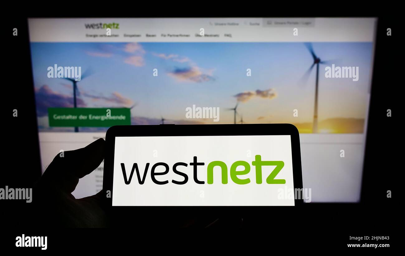 Person holding mobile phone with logo of German company Westnetz GmbH ...